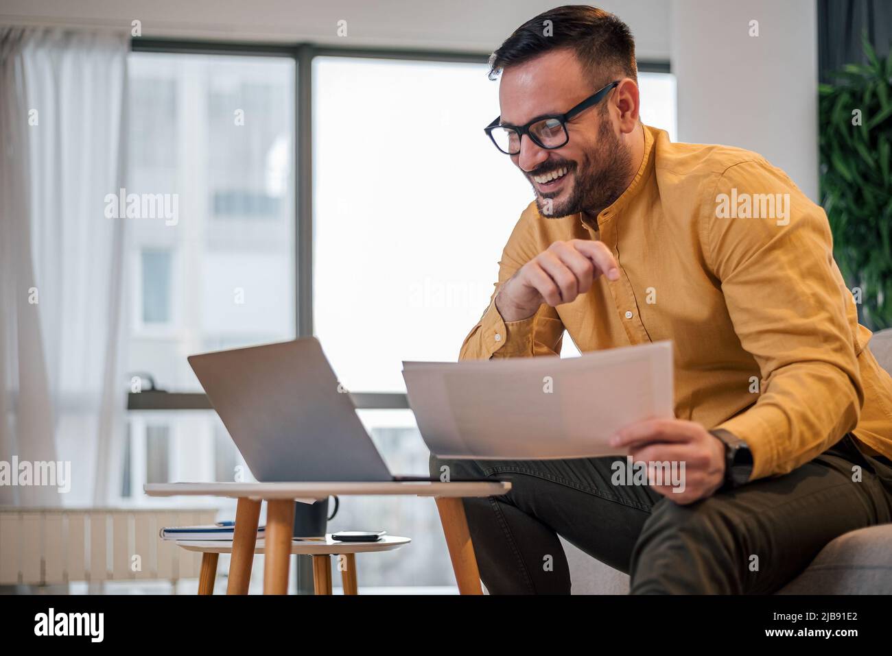 Smiling young freelancer reading documents. Businessman analyzing ...