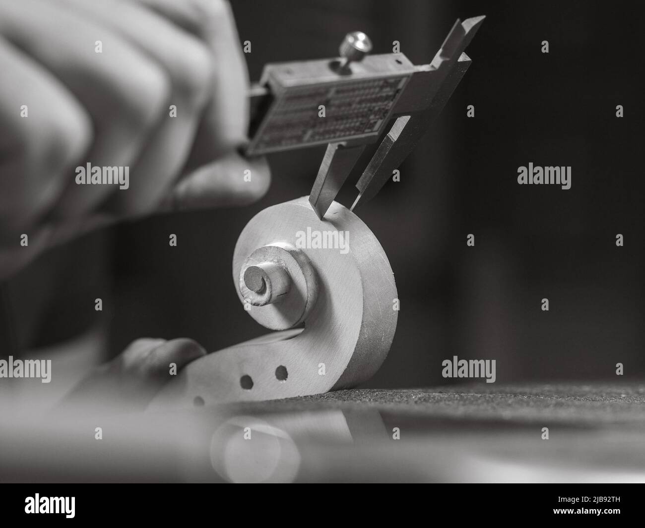 violin maker using a meter to shape and accurate measure fiddle scroll ...