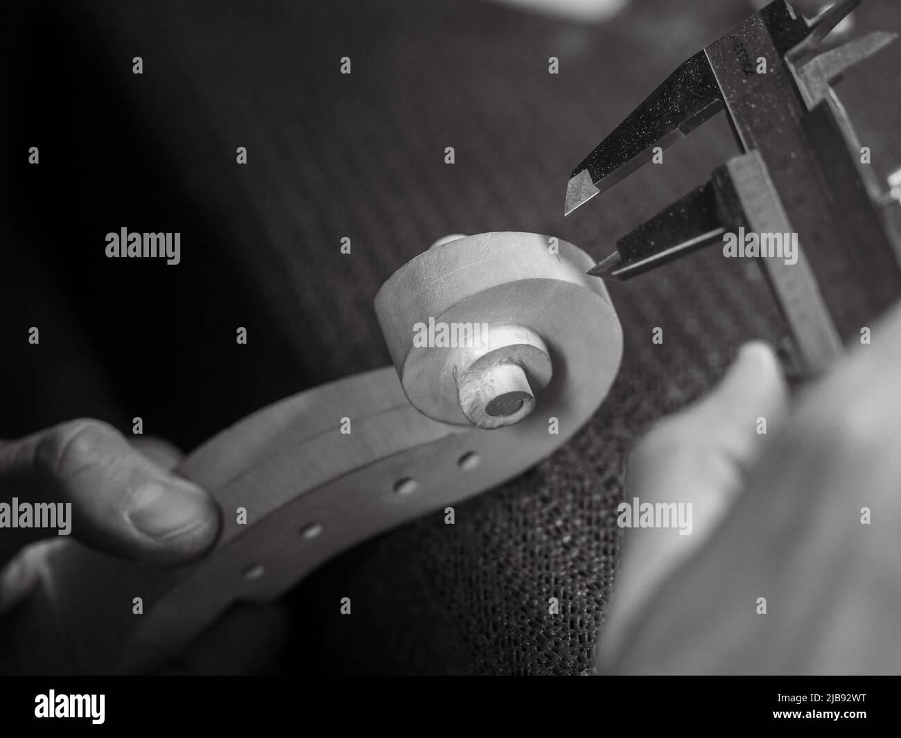 violin maker using a meter to shape and accurate measure fiddle scroll ...