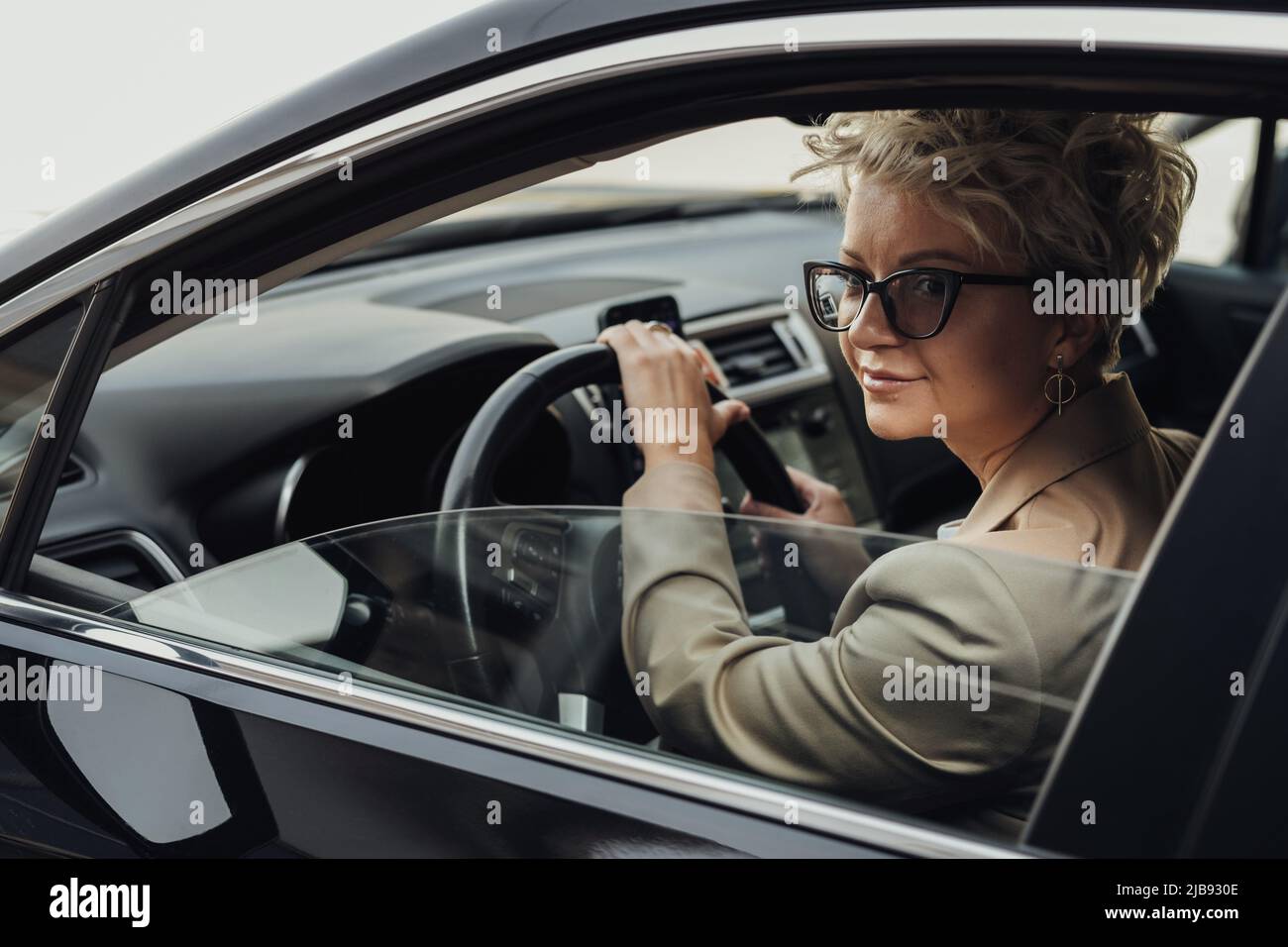 Fashionable Female Driver Looking Through the Window While Driving a ...