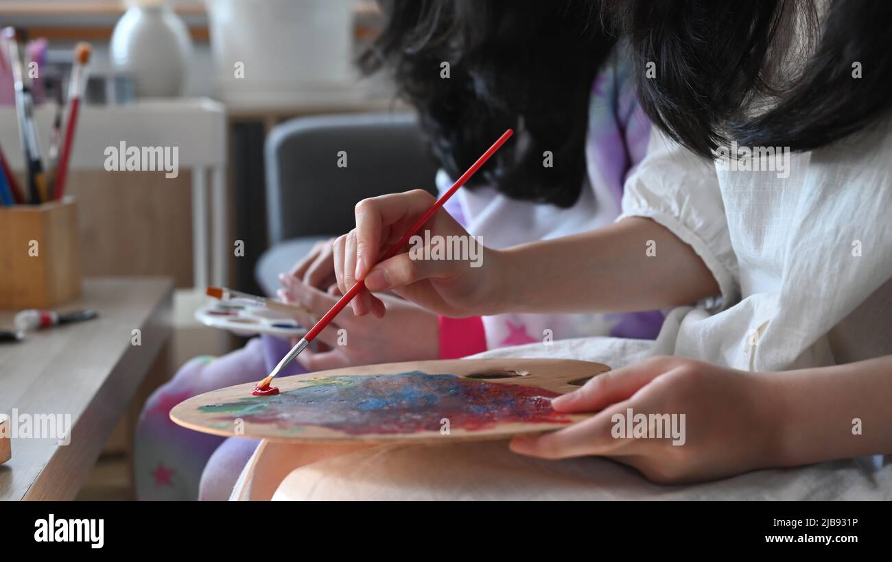 Two little girls or siblings enjoying painting with water color at home ...