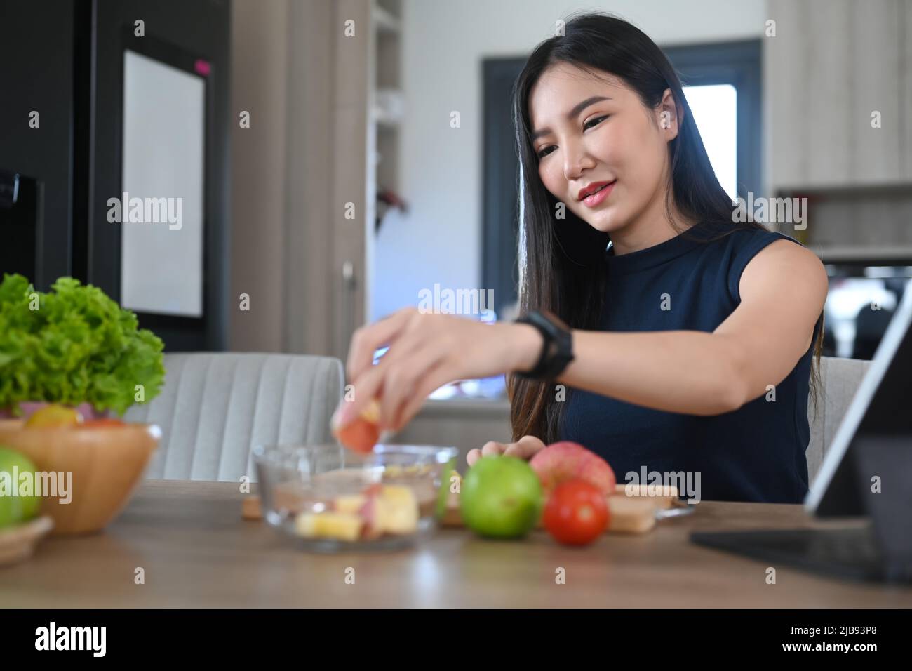 Healthy young woman making vegan meal with fresh vegetables and fruits ...