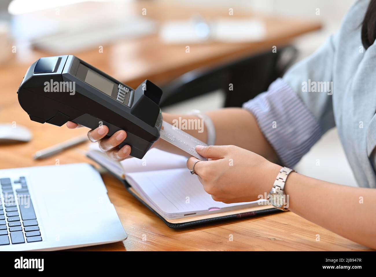 Young female customer swiping a debit card through payment terminal ...