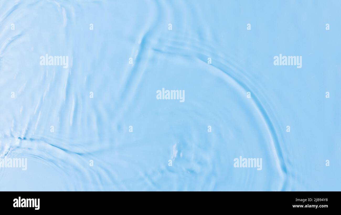 Rippling water surface and droplet on blue background close view from ...
