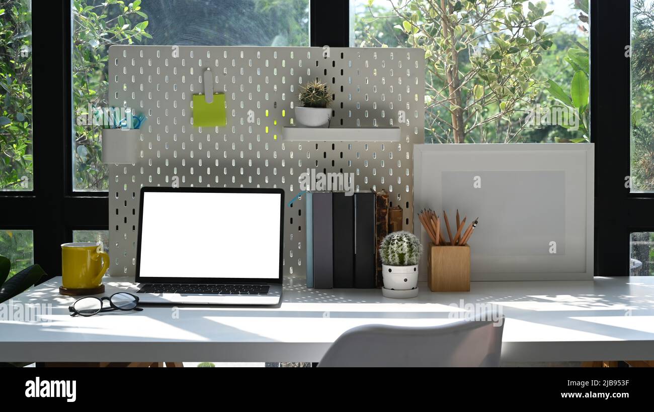 Laptop computer, potted plant and supplies at creative workplace. Blank ...