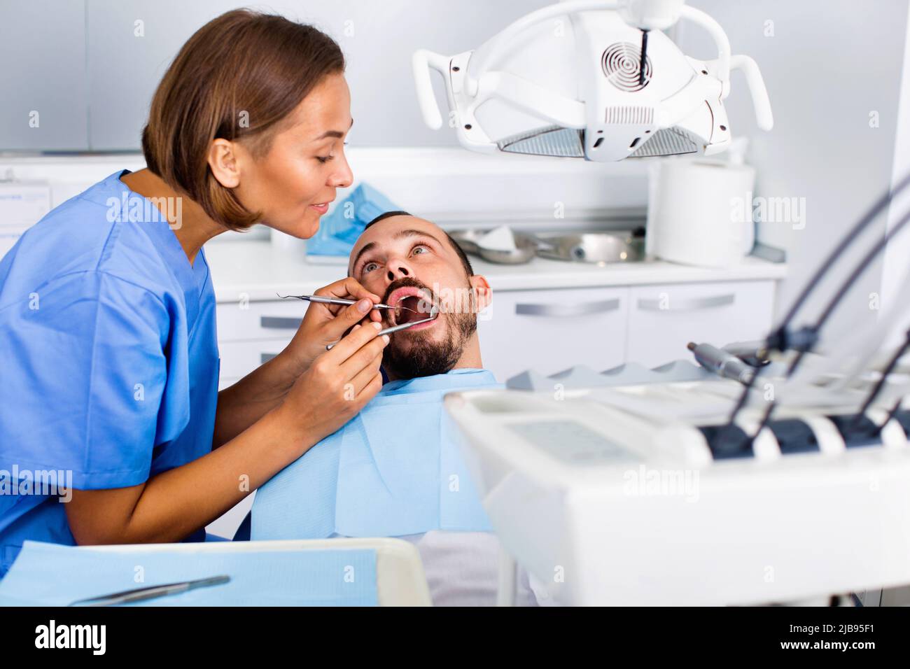 Stomatologist girl in uniform is taking visional inspection of a man ...