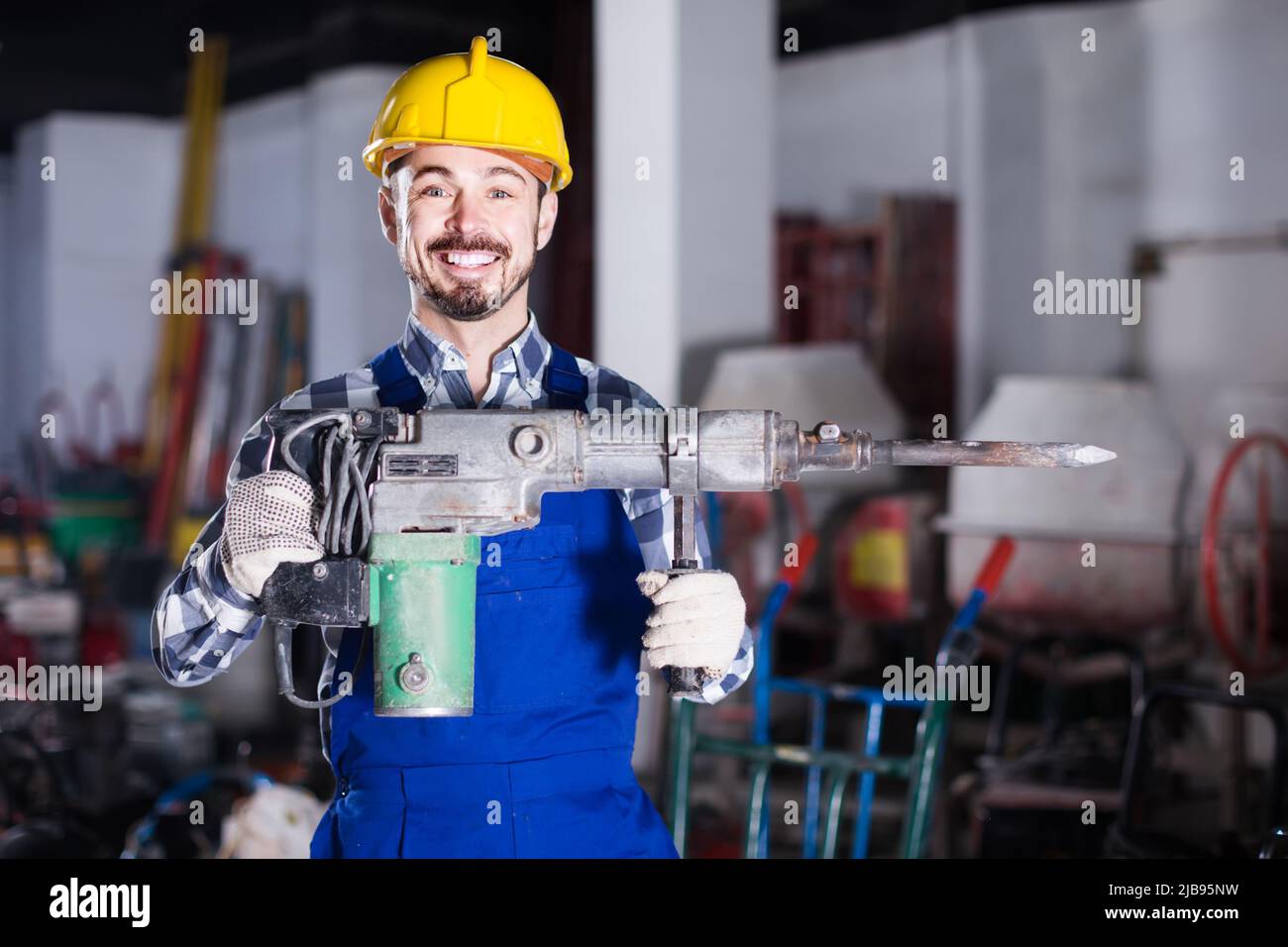 working man practicing his skills with pneumatic drill at workshop ...