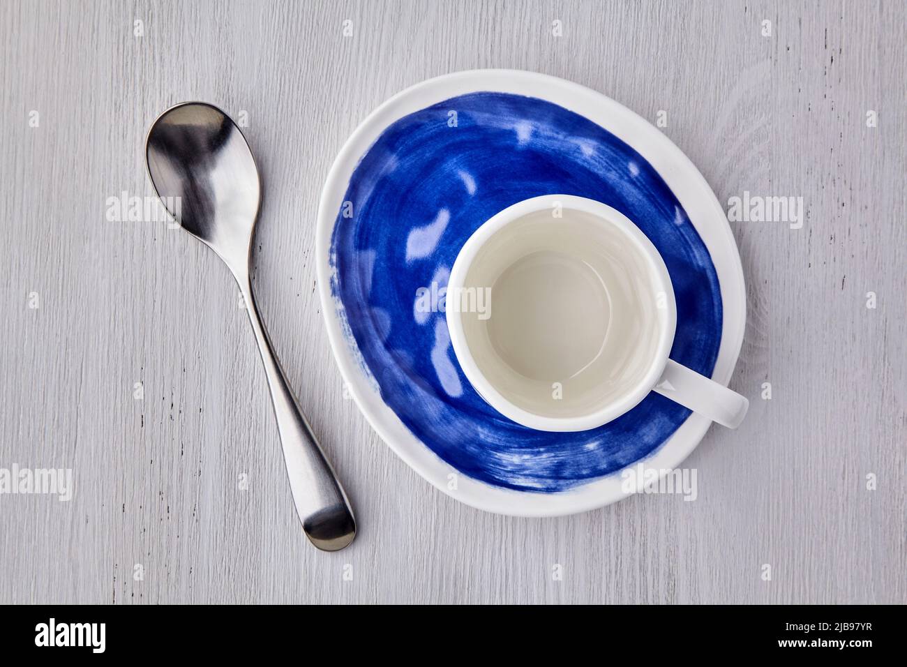 Empty white cup for hot drinks with a spoon on a blue plate on a white ...