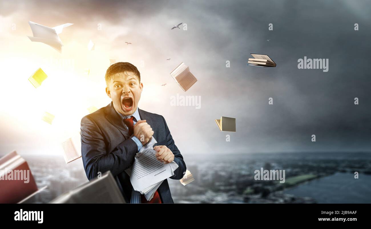 Young stressed man ripping documents with frustrated facial expression ...