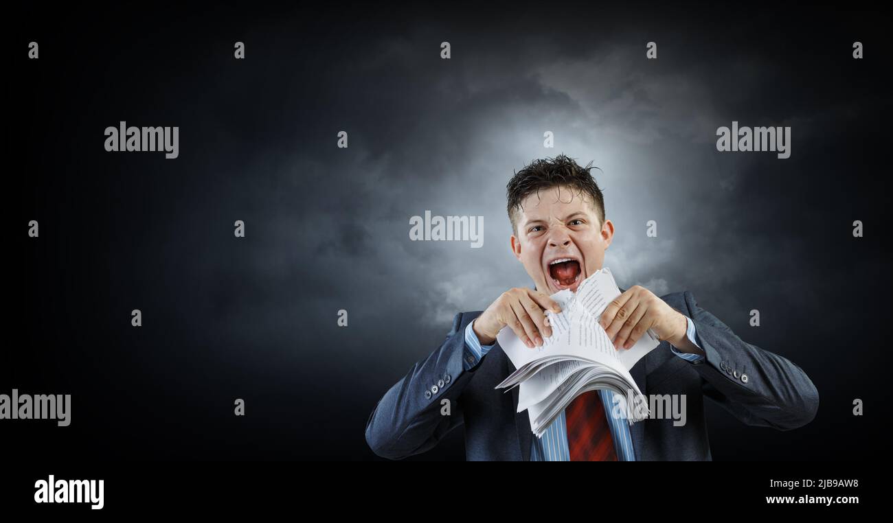 Young stressed man ripping documents with frustrated facial expression ...