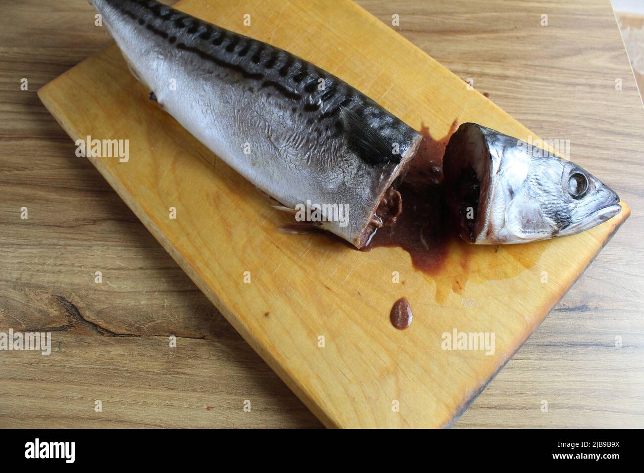 butchering fish. Cut off the head of a mackerel fish on a cutting board ...
