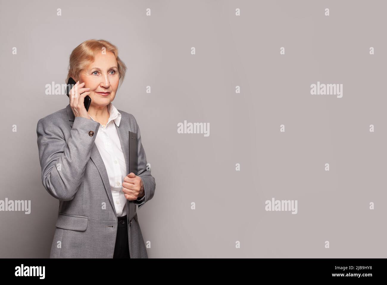 Attractive successful mature businesswoman working and making phone ...