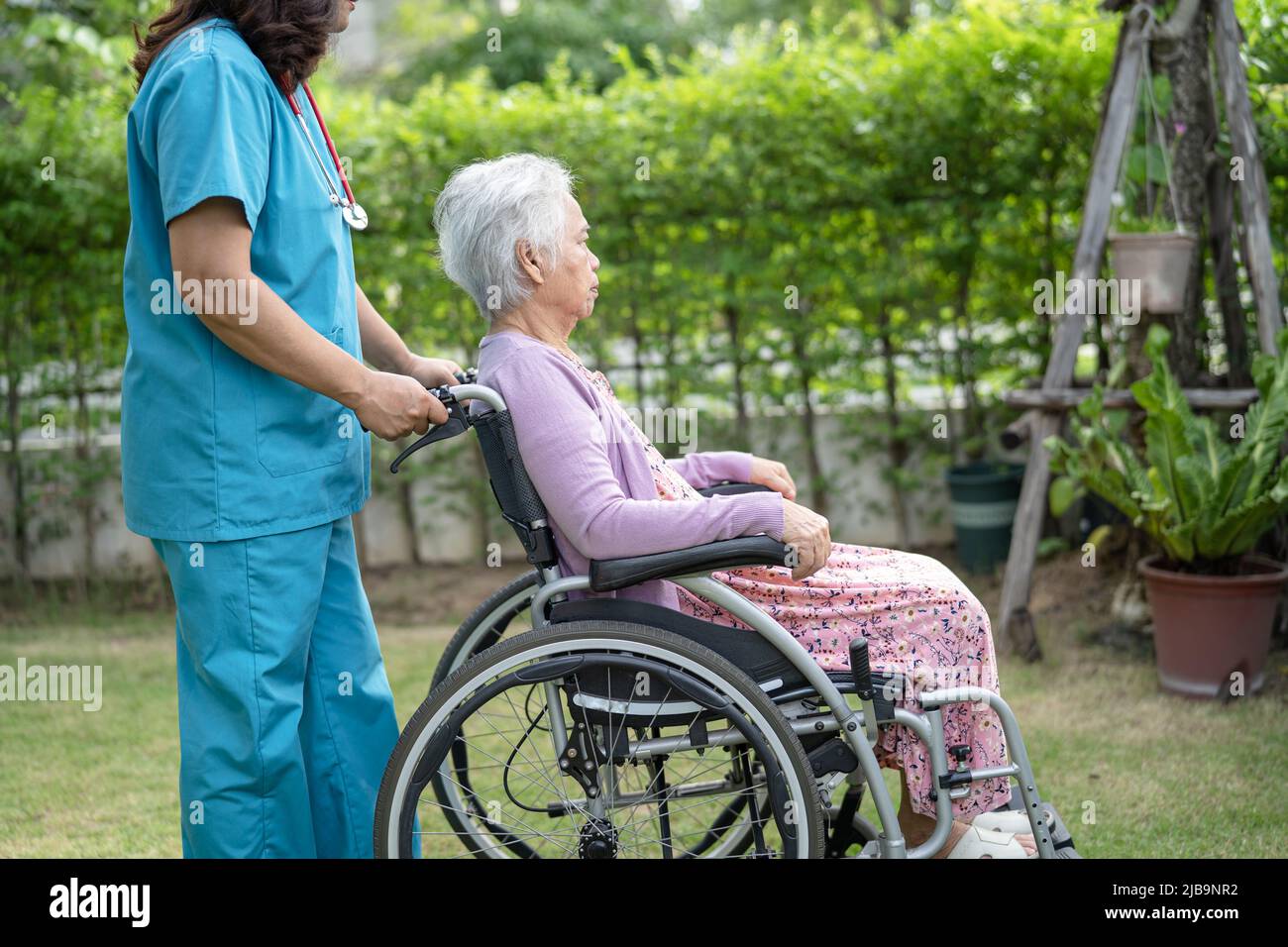 Doctor caregiver help and care Asian senior or elderly old lady woman patient sitting on ...