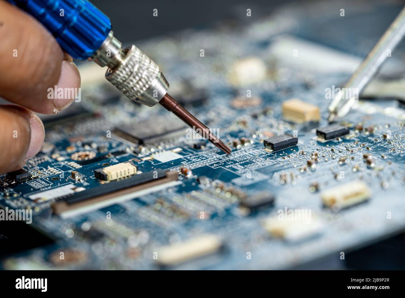 Technician repairing inside of mobile phone by soldering iron ...