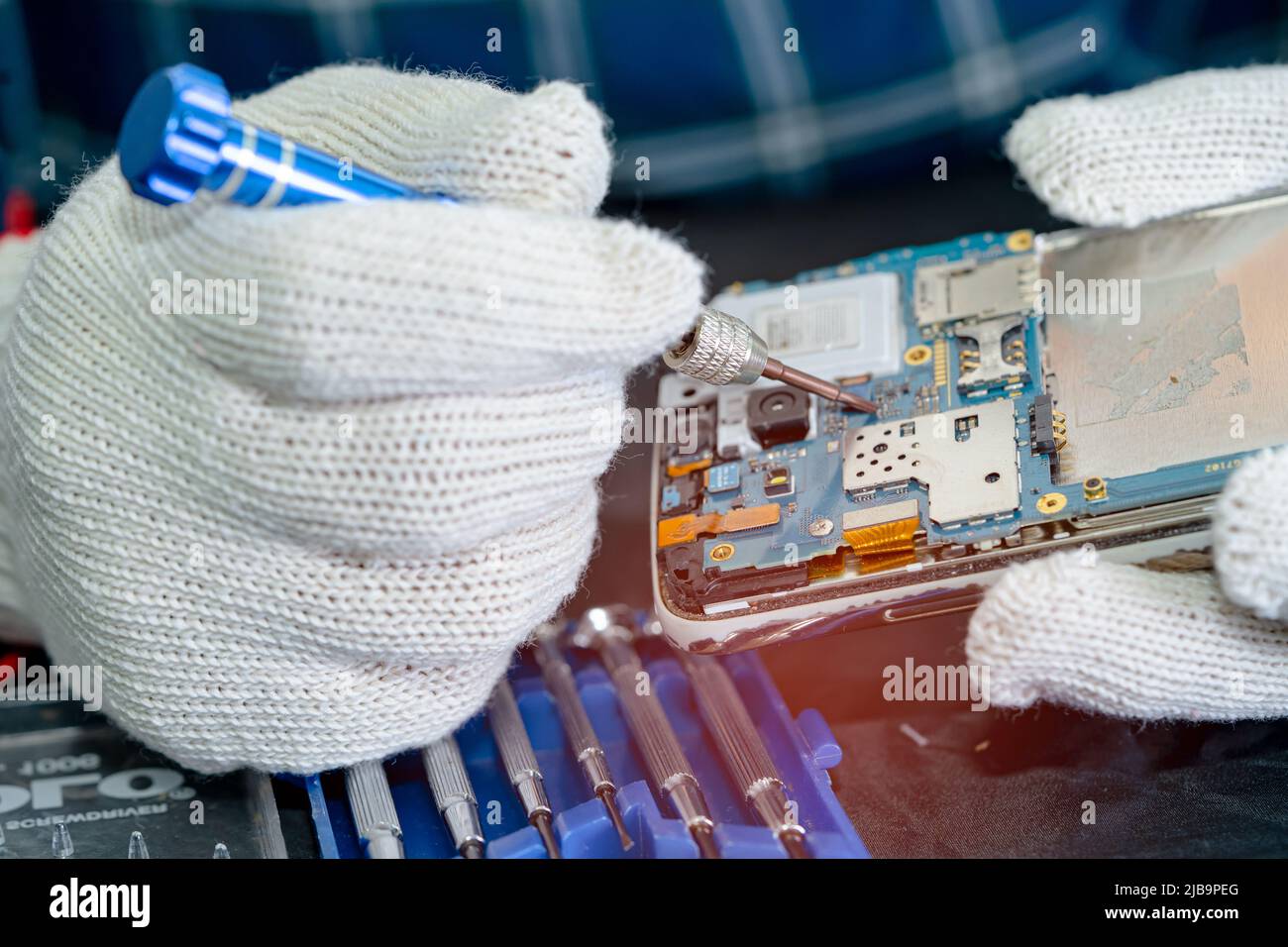 Technician repairing inside of mobile phone by soldering iron ...