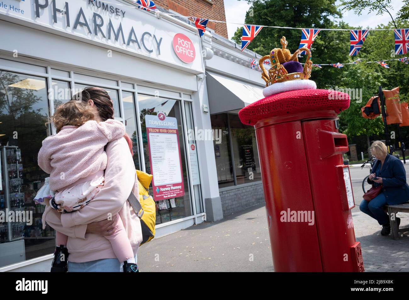 A crocheted knitted crown sits on top of a Royal Mail postal box in ...