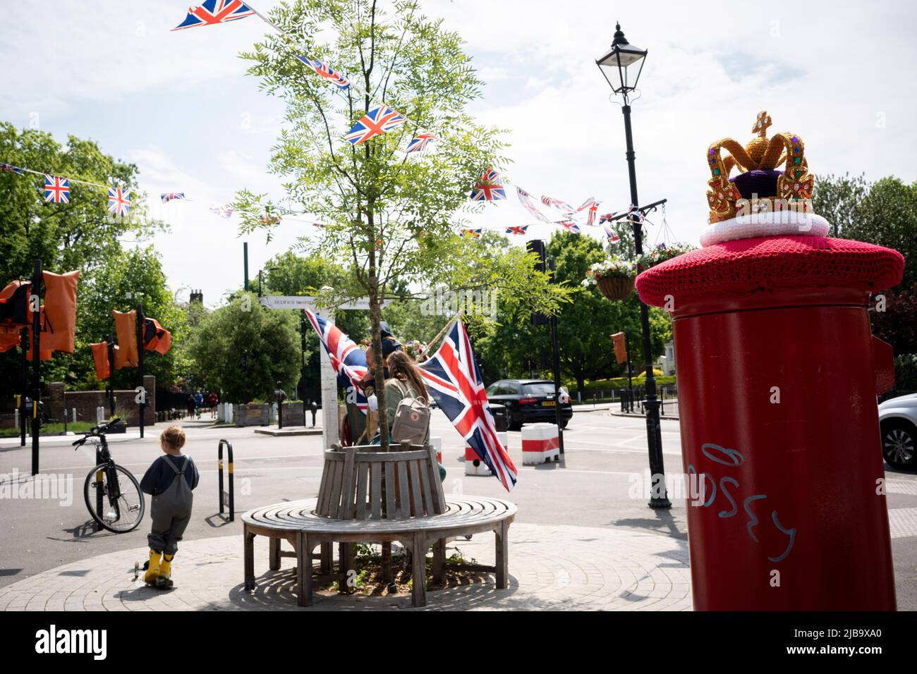 A crocheted knitted crown sits on top of a Royal Mail postal box in ...