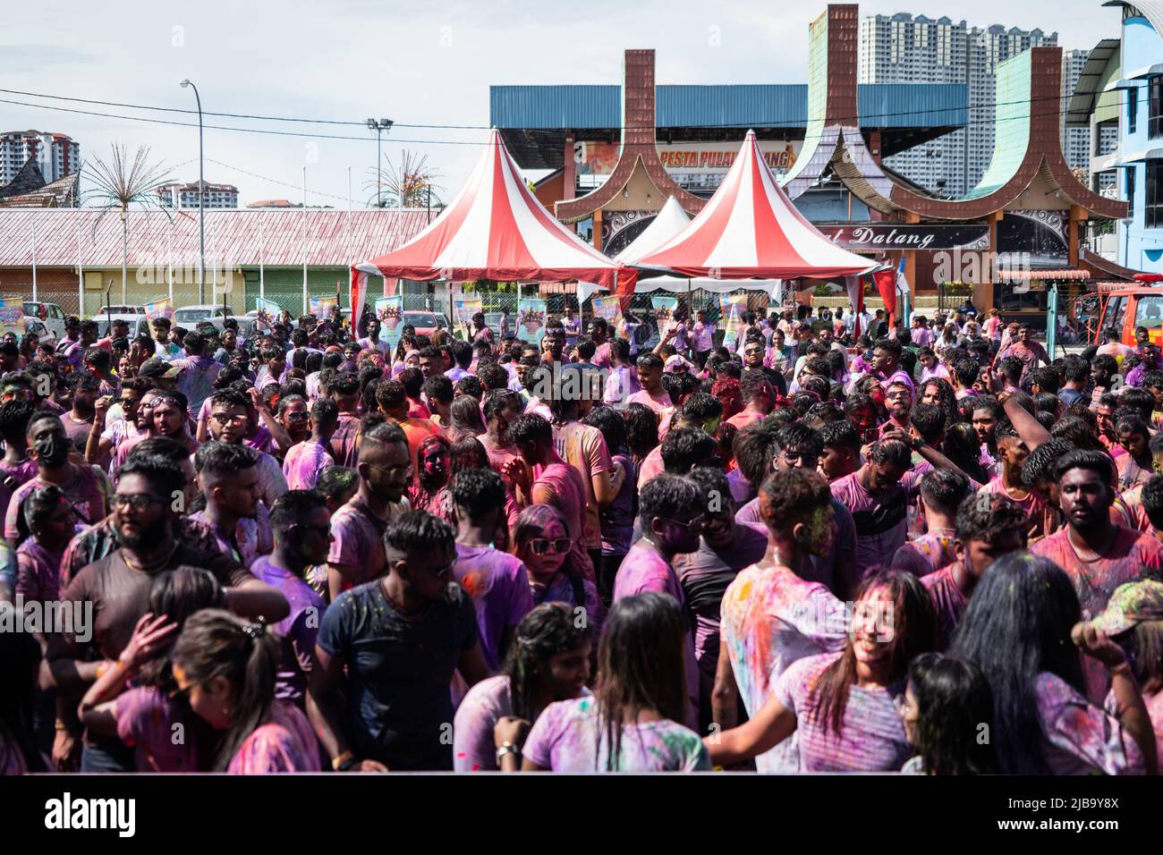 Festival goers covered in colorful powder dance together during a live ...