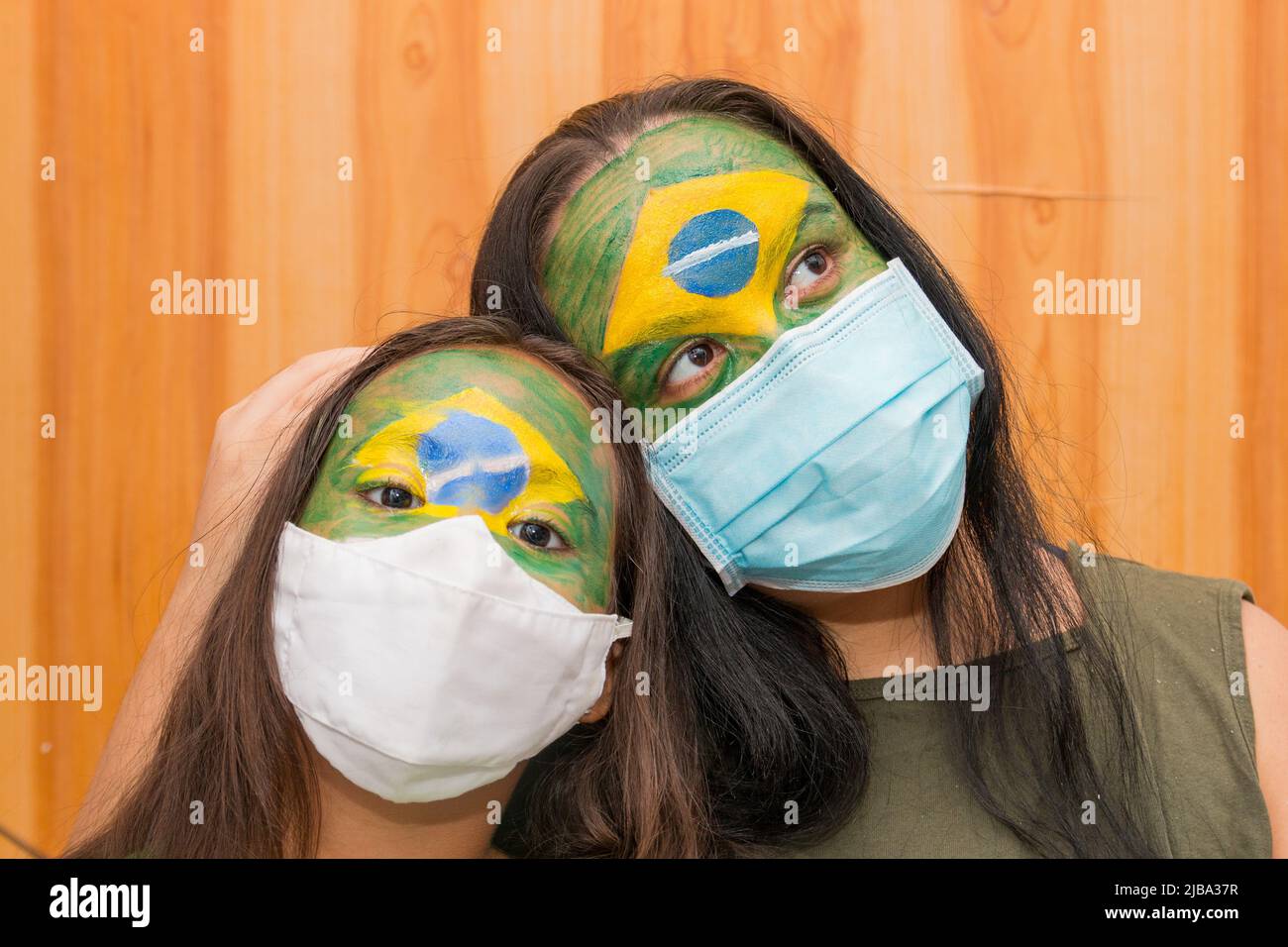 mother and daughter with mask and brazil flag painted on their face in ...