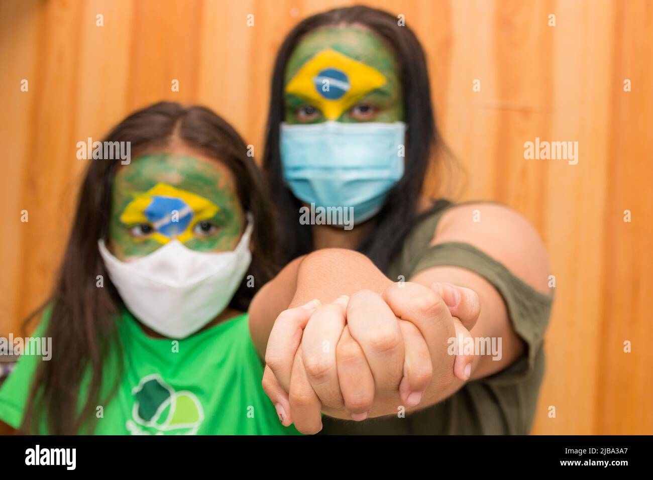 mother and daughter with mask and brazil flag painted on their face in ...