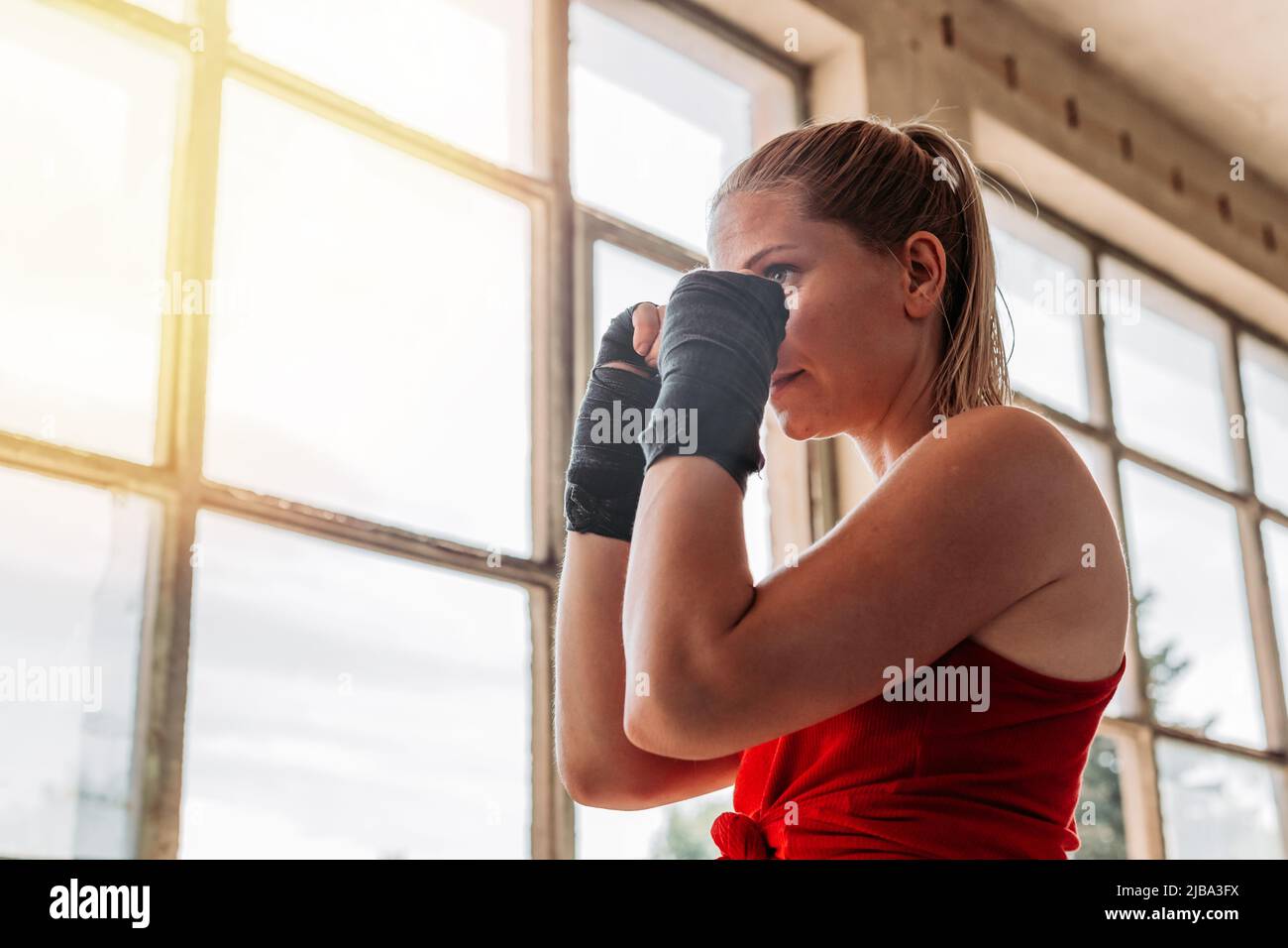 Portrait of young, fit female boxer with bandage on her hands in ...