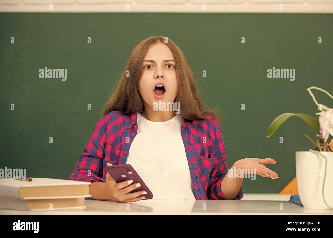 shocked teen girl typing message on mobile phone in high school at ...