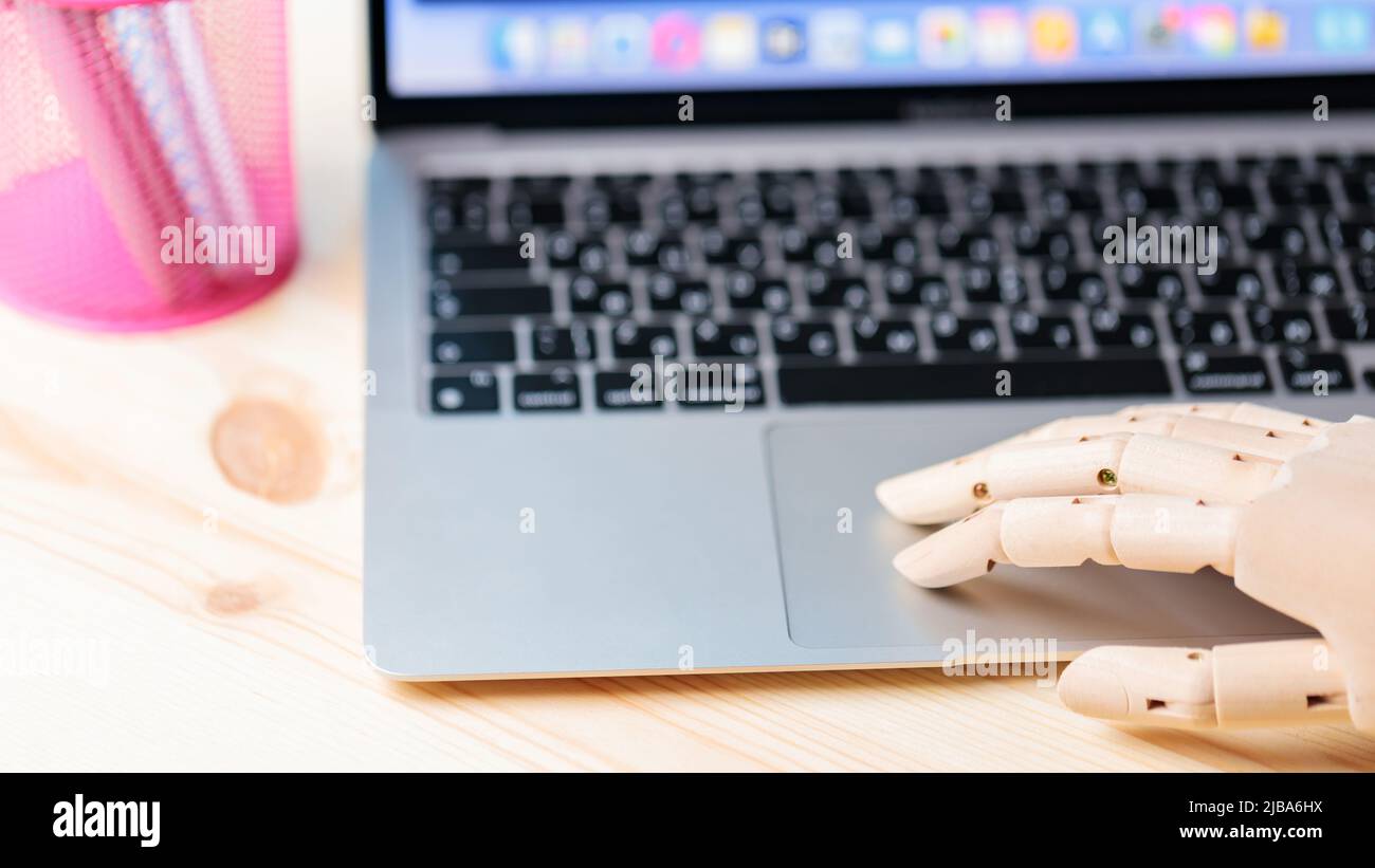 Robotic arm using laptop on a wooden table. Artificial intelligence ...
