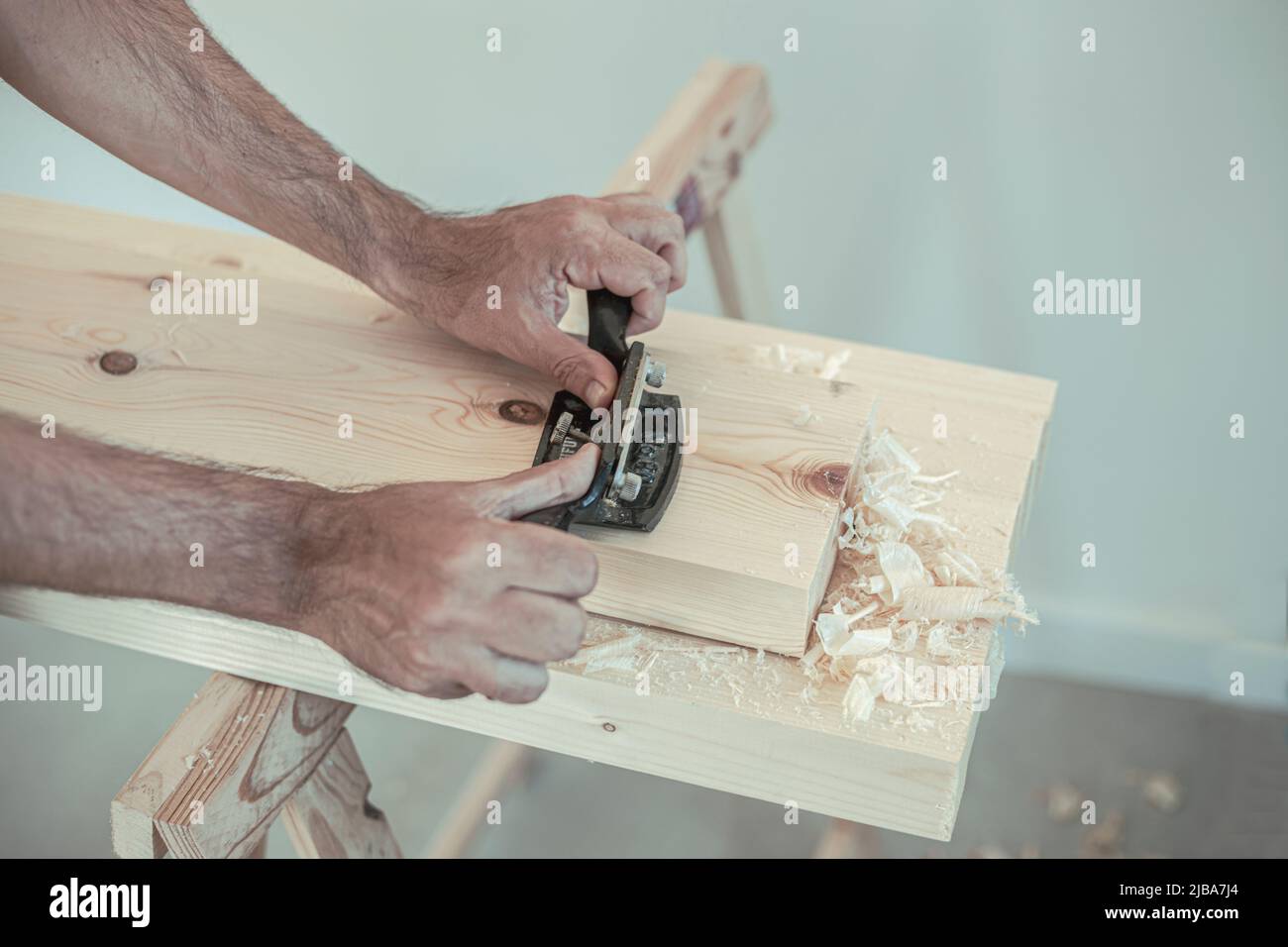 Two man's hands using a cabinet scraper to work on a wooden slat in an ...