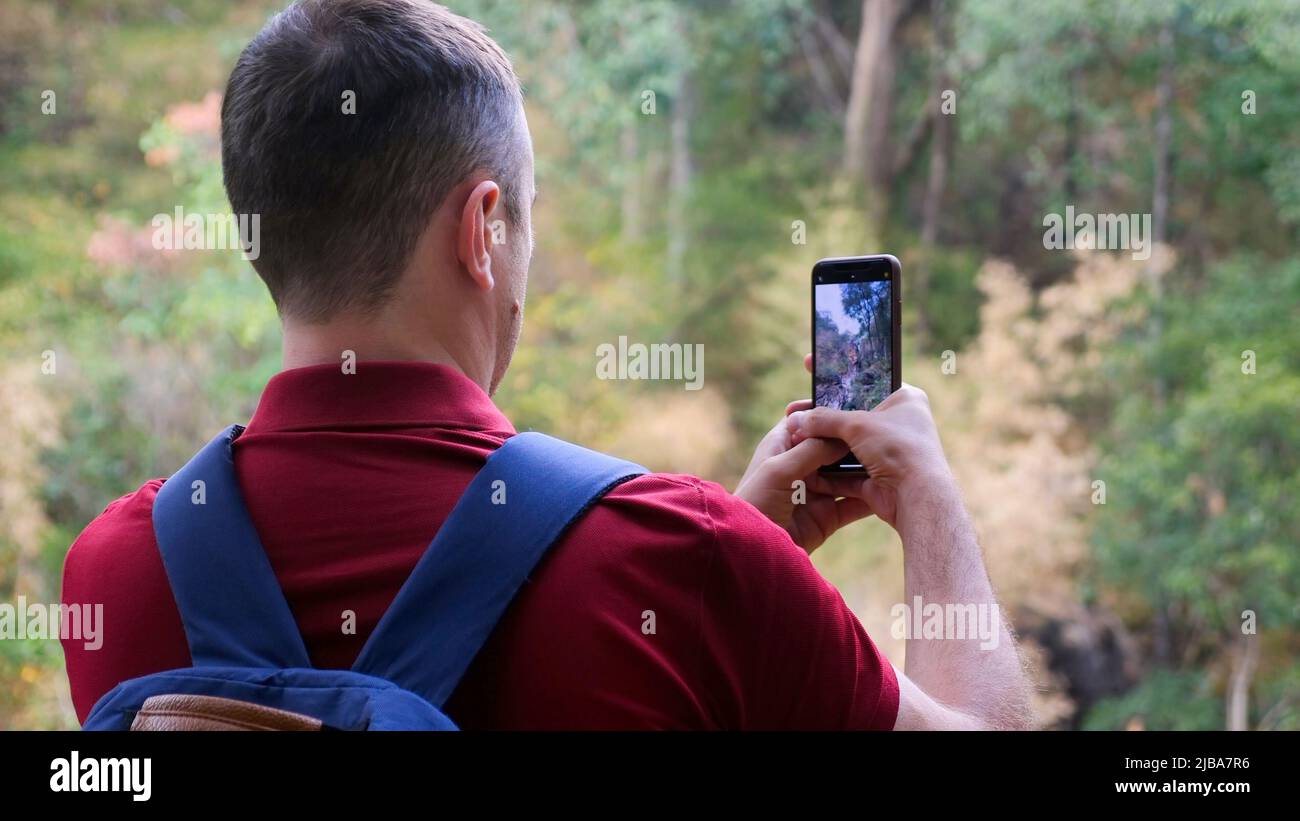 Male traveler blogger with backpack in nature filming video on ...