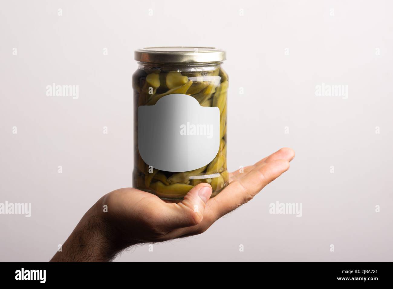 Pickled okra conserve with round cap inside hand, editable mock-up ...