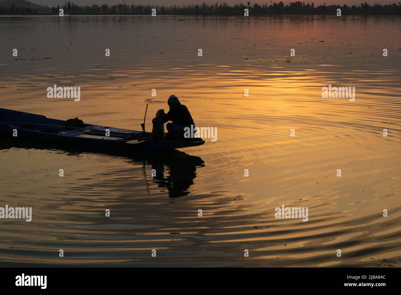 June 4, 2022, Srinagar, Jammu and Kashmir, India: A Kashmiri cleans his net during sunset on Dal ...