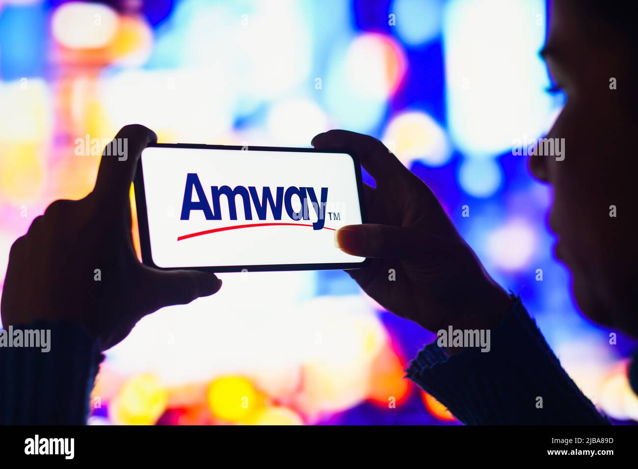 In this photo illustration, a silhouetted woman holds a smartphone with ...
