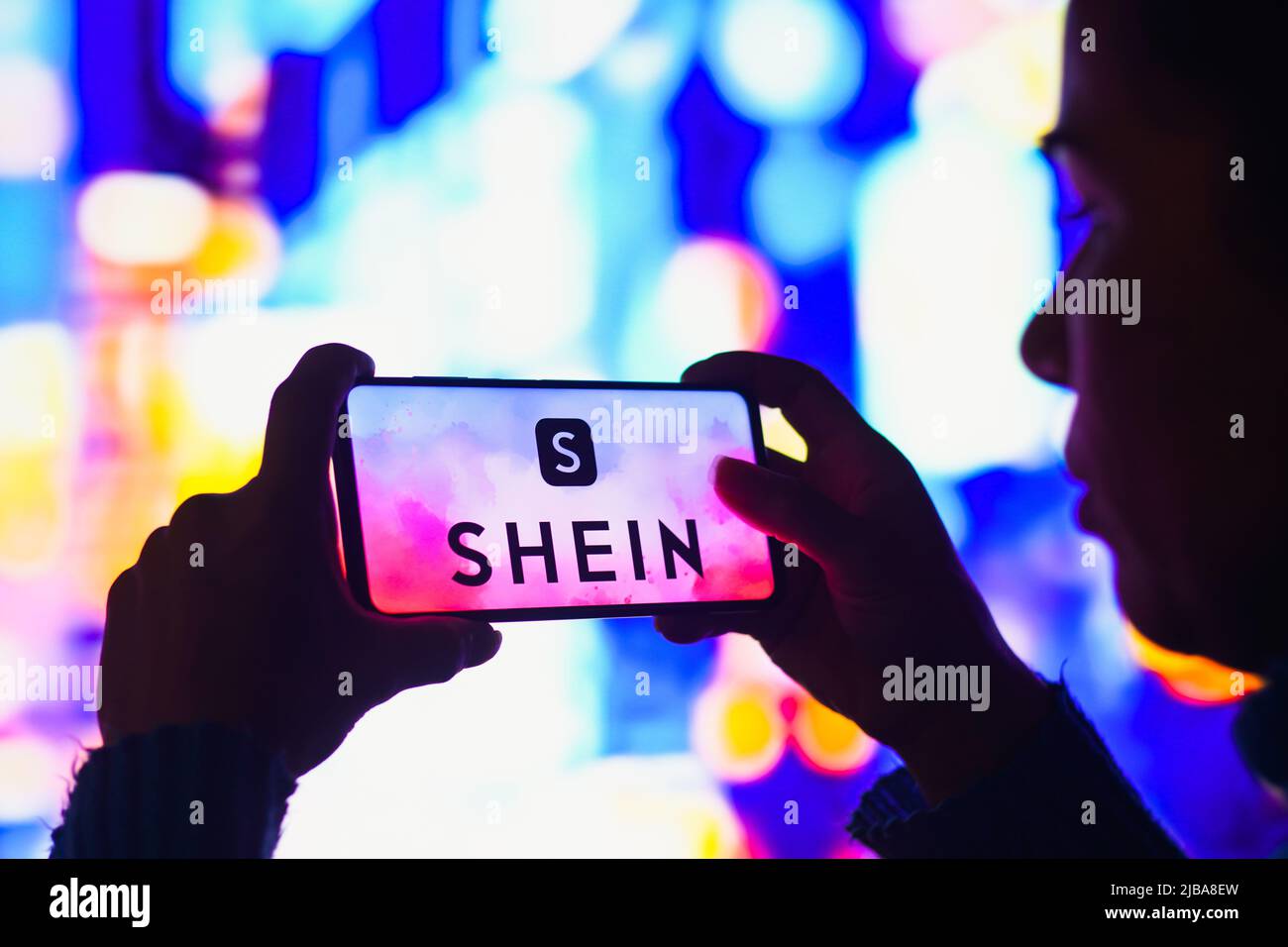 In this photo illustration, a silhouetted woman holds a smartphone with ...