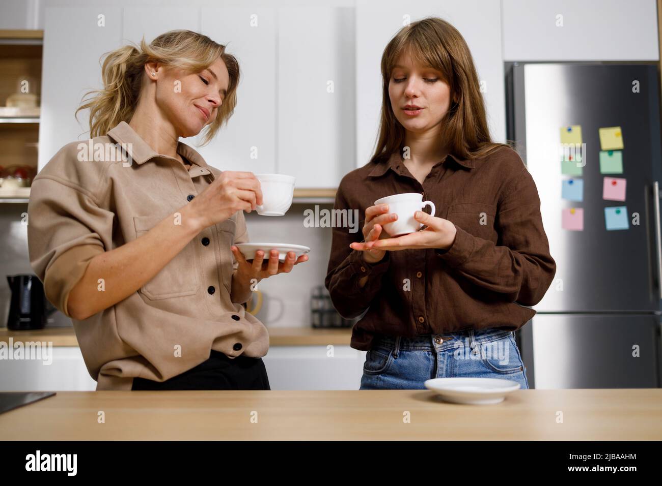 Mom and daughter drink coffee and cosy chat in the kitchen Stock Photo ...