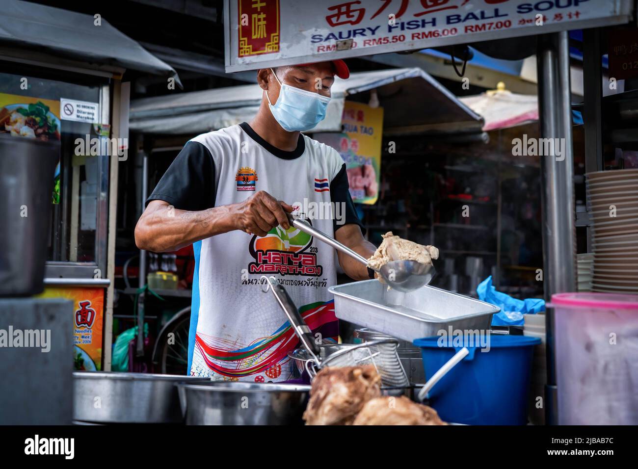 A street food vendor uses a ladle to make soup on the street in George ...