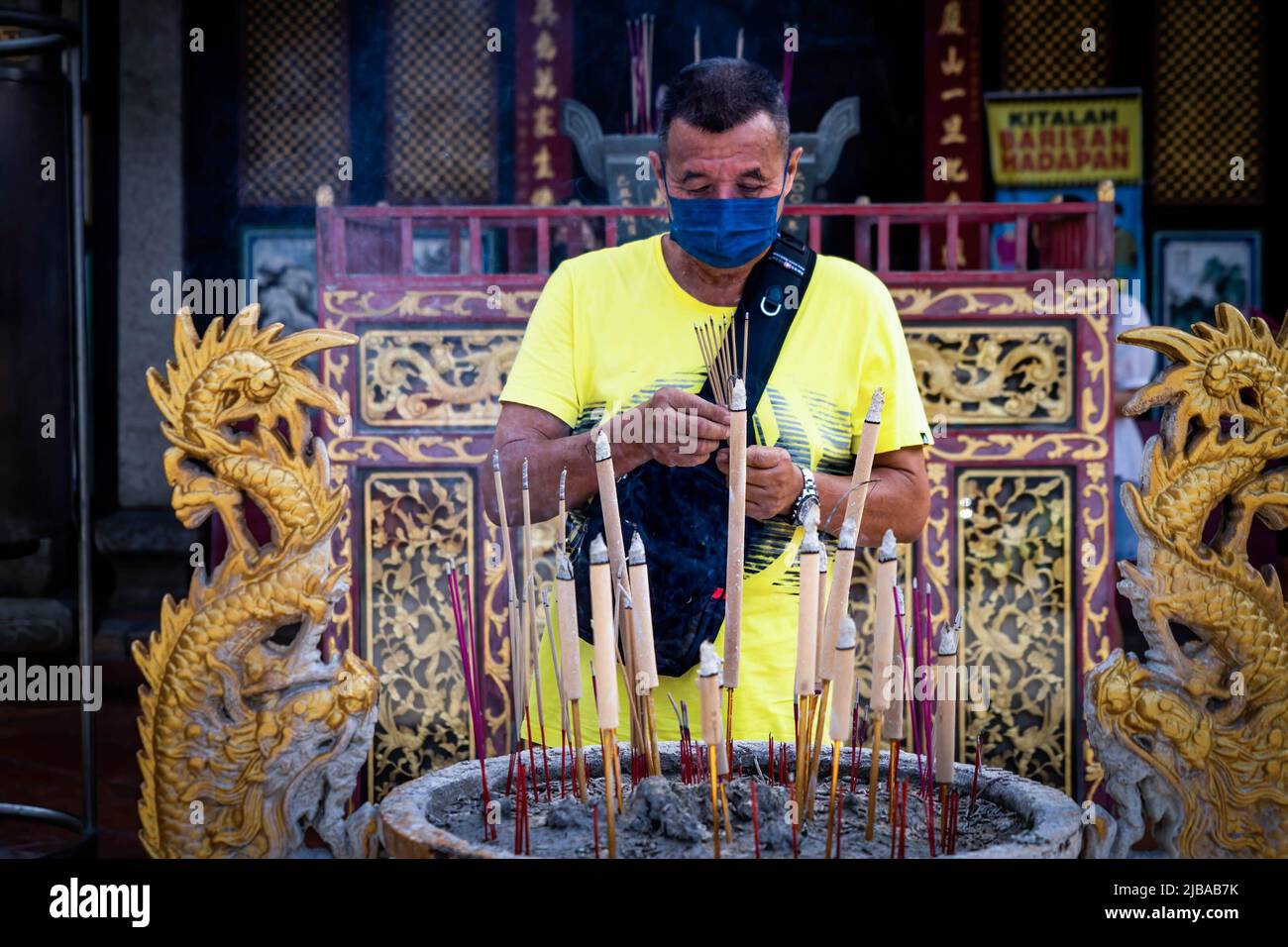 A Buddhist person lights incense as part of a prayer ritual at a ...