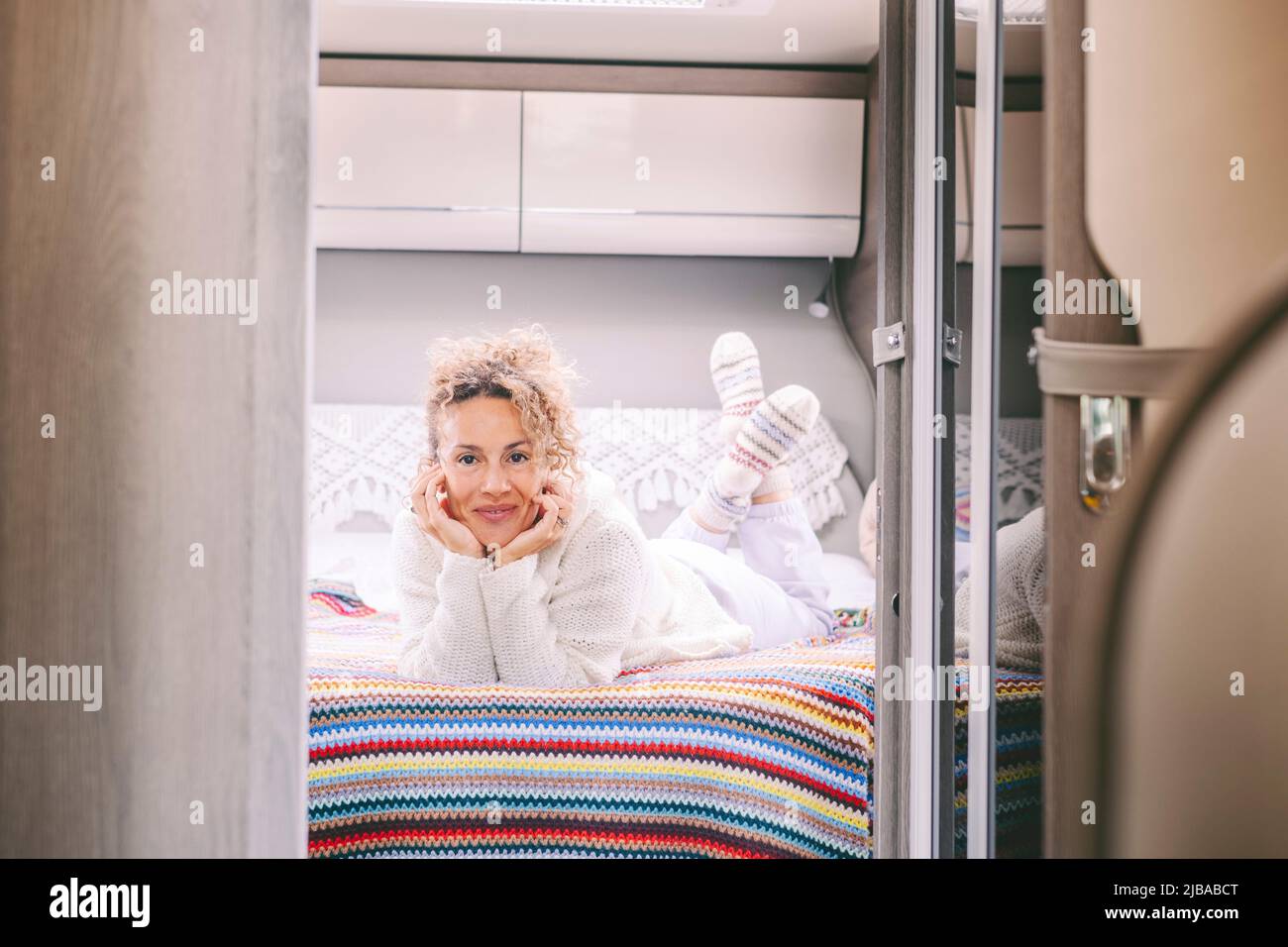 Portrait of cheerful pretty adult woman laying and smiling inside her ...