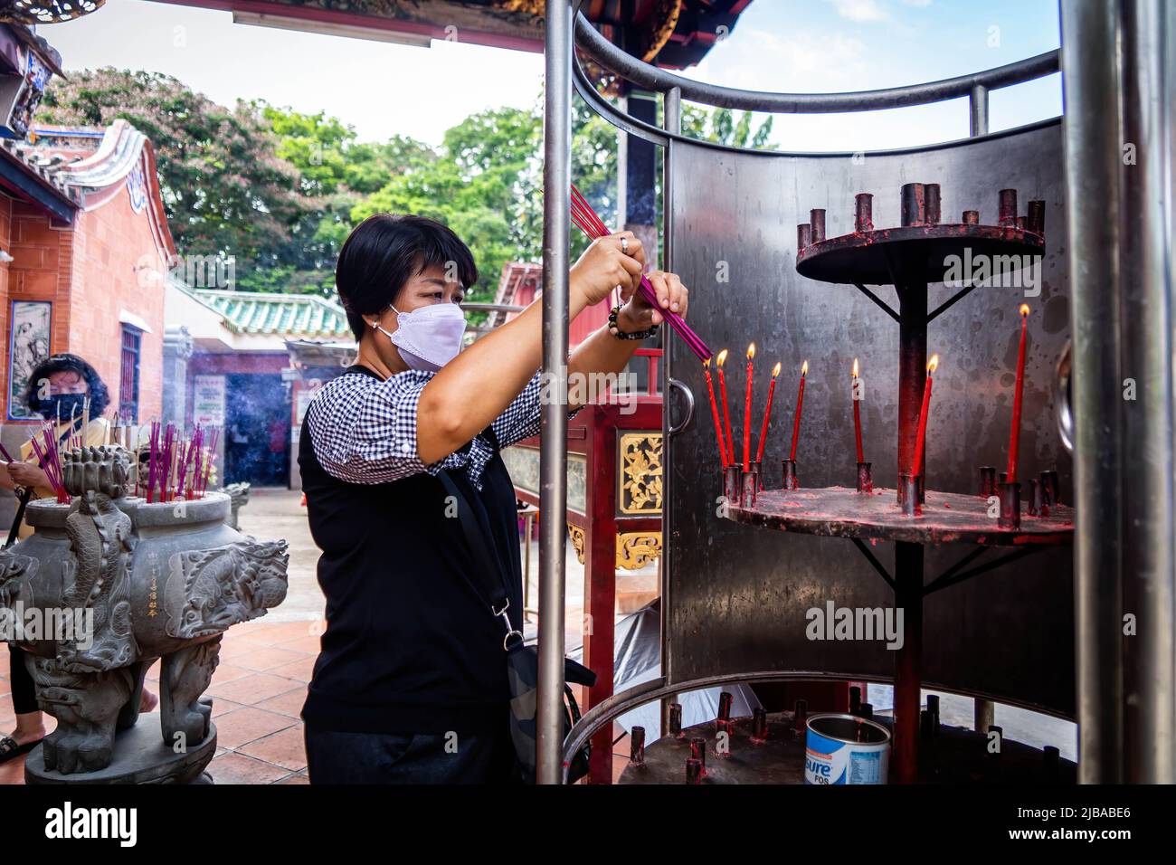 A Buddhist person lights incense as a part of a prayer ritual at a ...