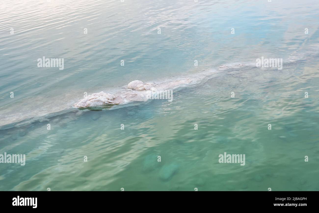 Sand covered with crystalline salt on shore of Dead Sea, clear calm ...