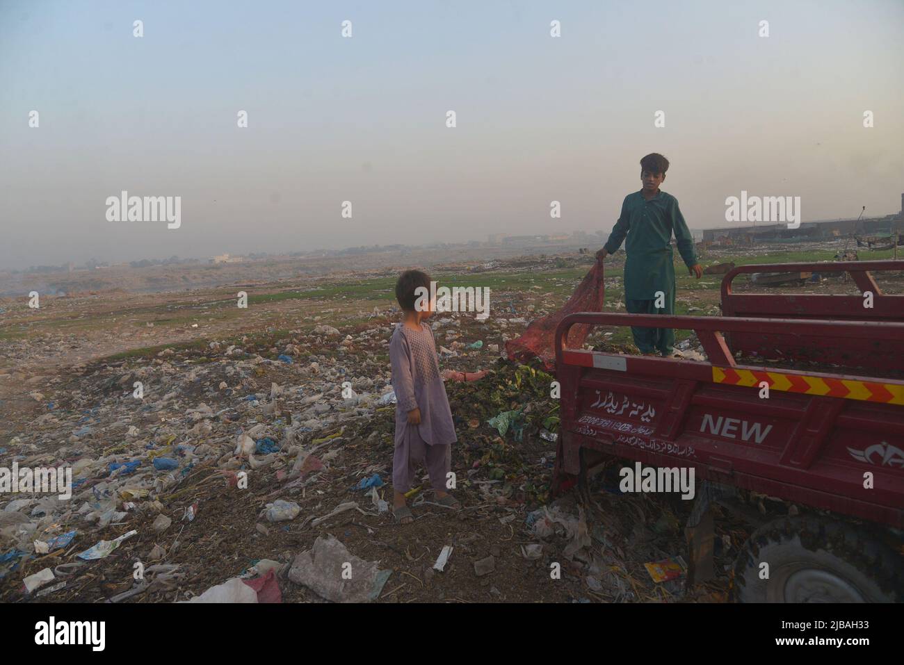 Pakistani people busy in their routine work near a garbage dump site ...
