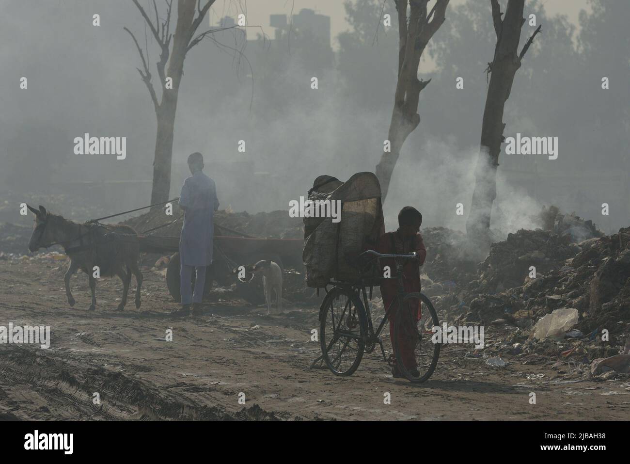 Pakistani people busy in their routine work near a garbage dump site ...