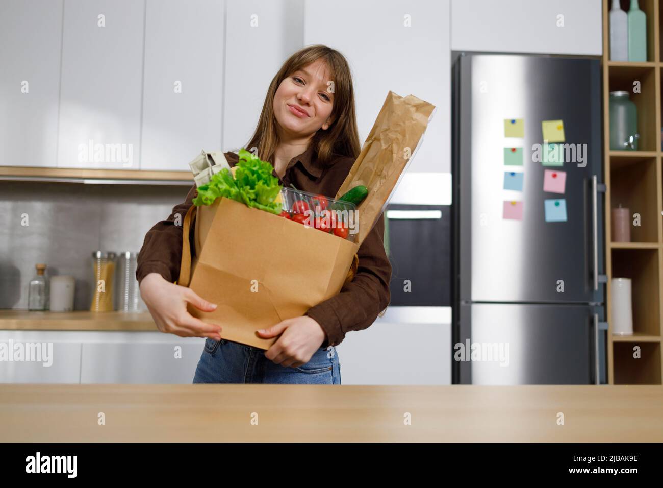 Pretty young woman holding a grocery bag full of fresh and healthy food ...