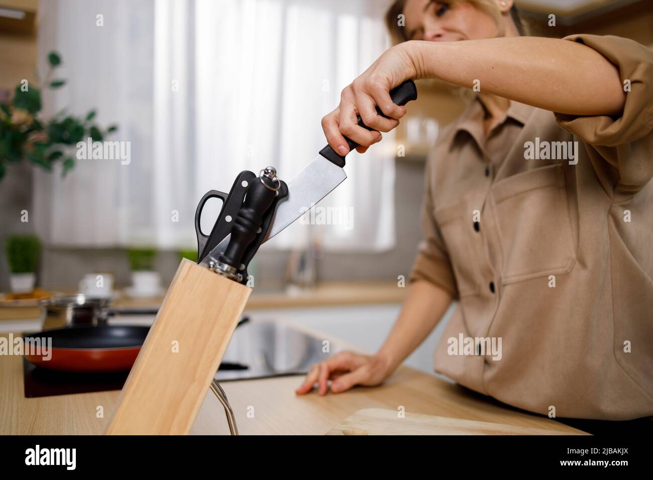 Woman pulling out a kitchen knife from a wooden block Stock Photo - Alamy