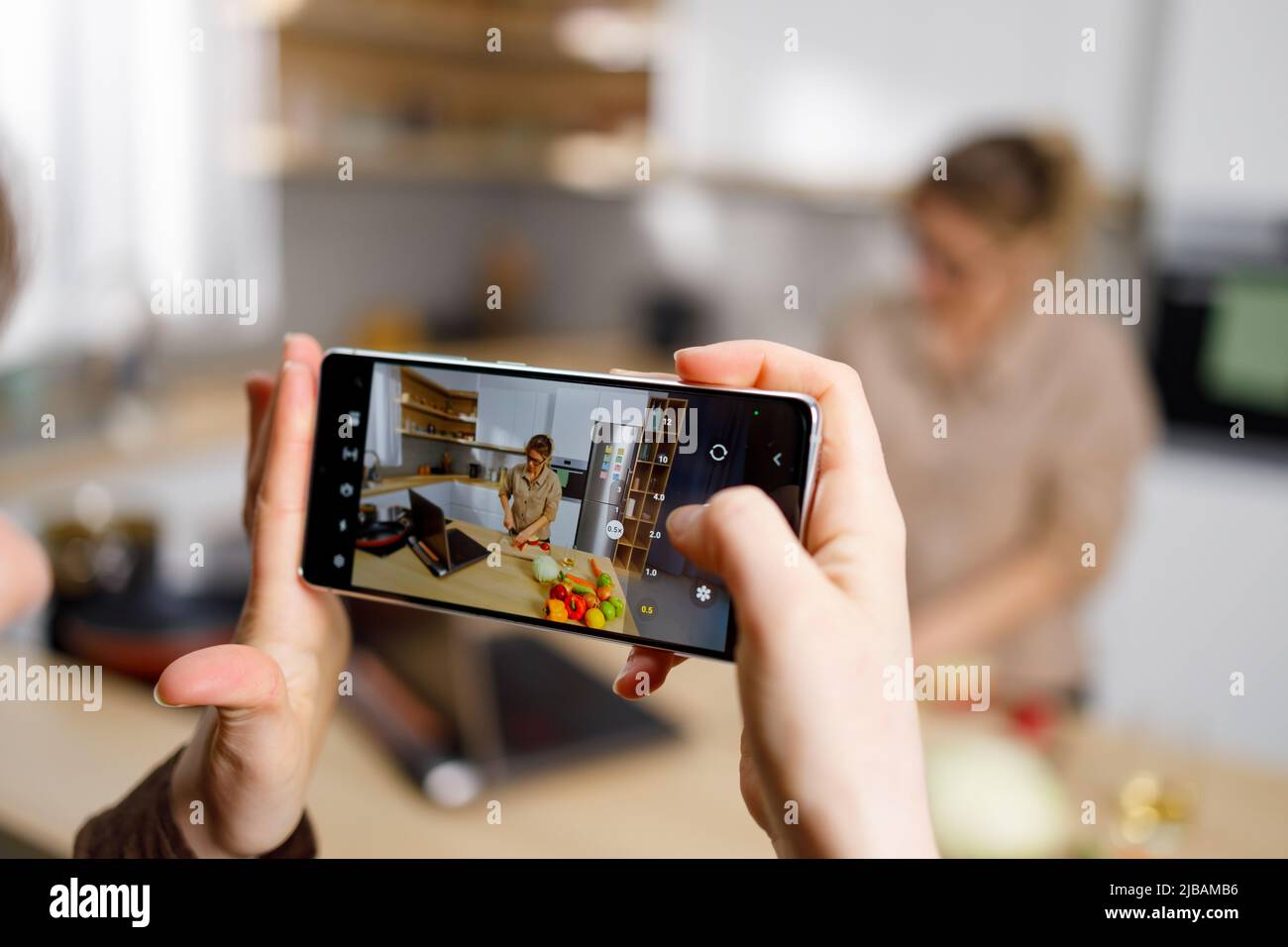 Girl with smartphone recording video of her mother cooking Stock Photo ...