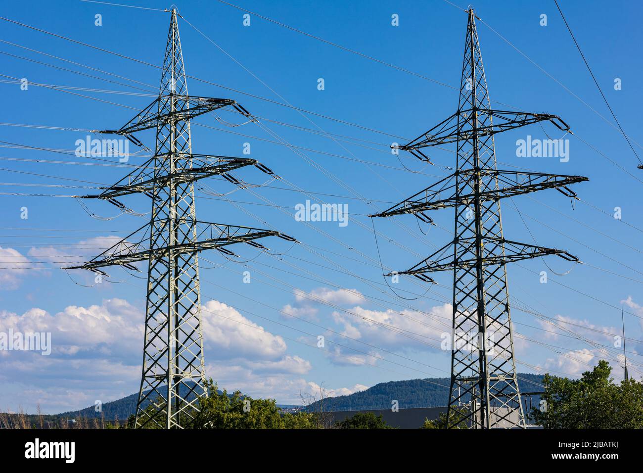 Electrical net of poles on a panorama of blue sky and green meadow ...