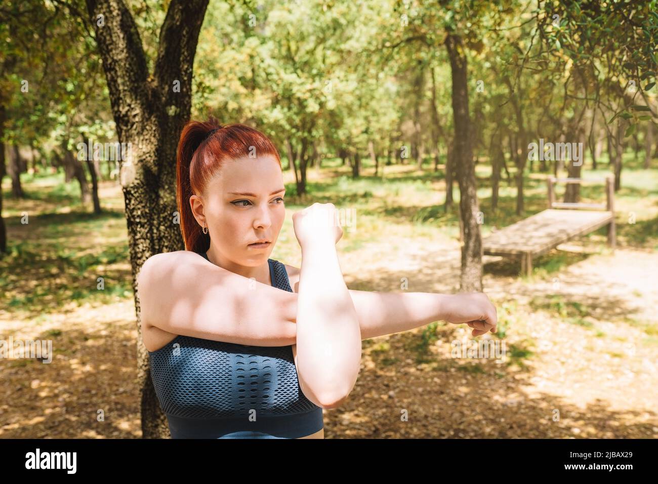 young athlete woman, doing arm stretching exercises to warm up the body ...