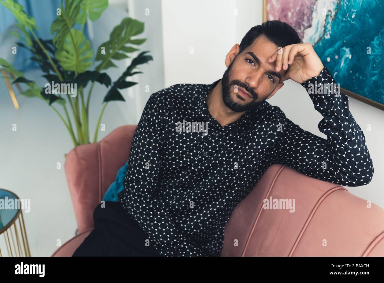 Young man sitting on coach rest at home after a hard day at work. High ...