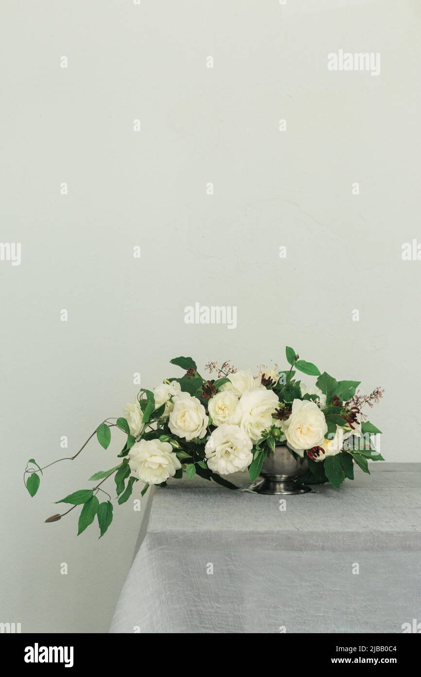 A beautiful white rose floral arrangement on a dinner table with ...