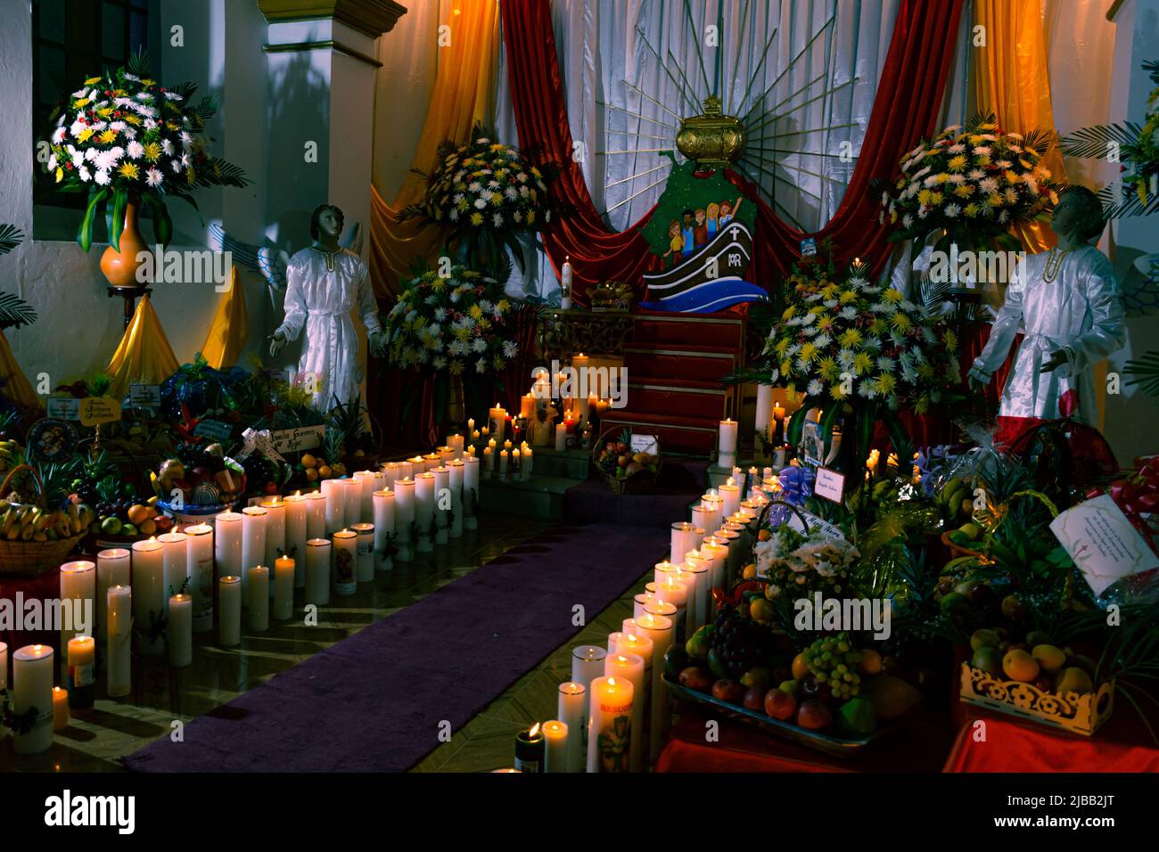 catholic altar decorated with white candles and frutal arrangements ...