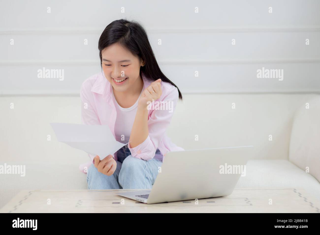 Young asian business woman working on laptop computer and looking graph ...